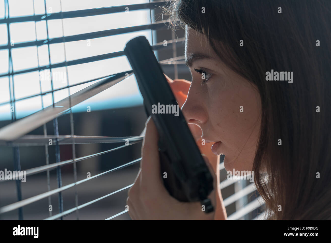young woman with a gun at the window Stock Photo - Alamy