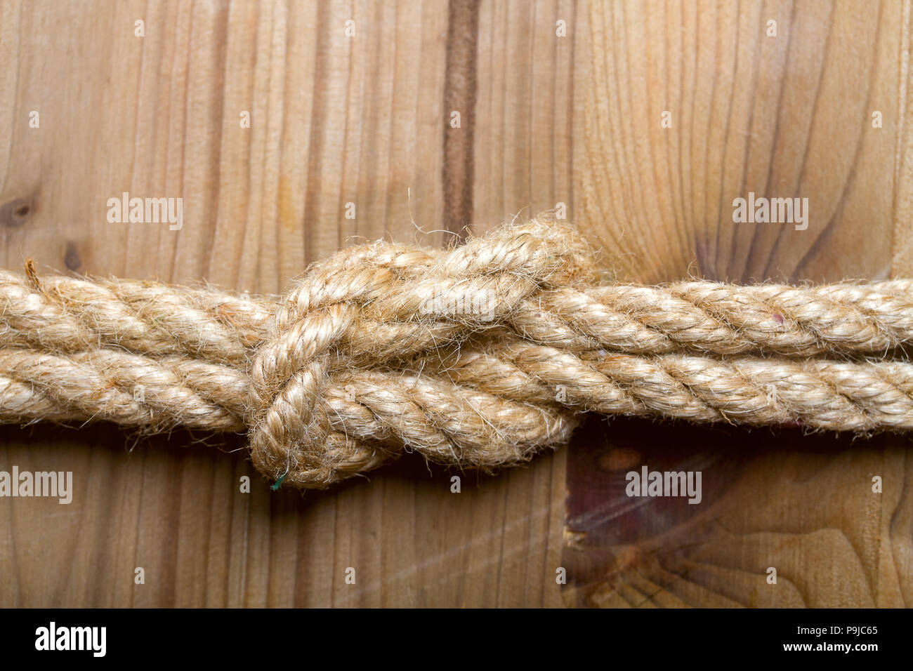 sea knot of rough rope on a simple wooden light brown background Stock ...