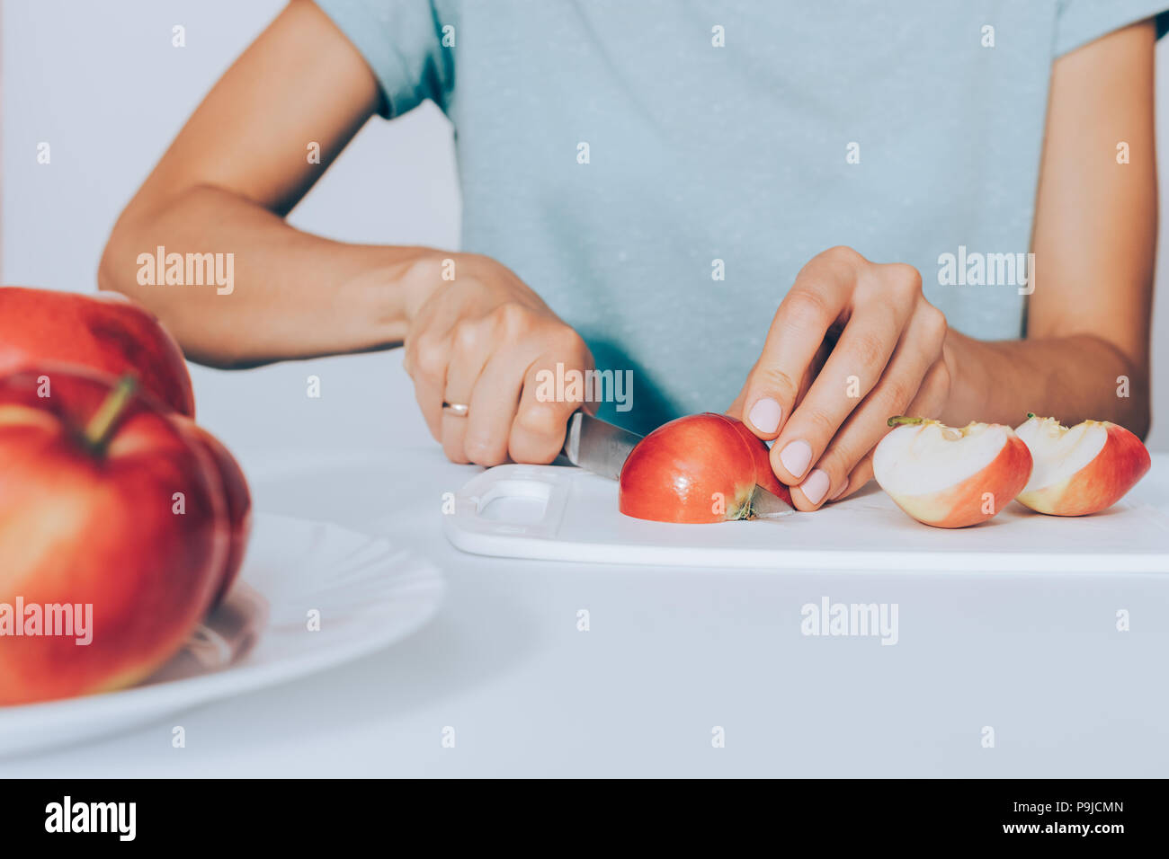 Young woman cutting red apple. Close-up of female's hands dividing ...