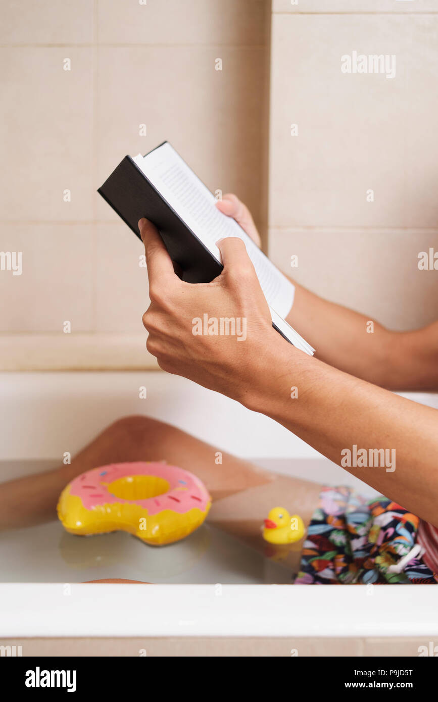 closeup of a young caucasian man wearing a swimsuit reading a book in ...