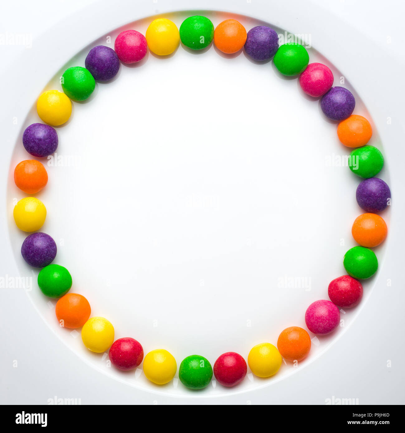 Circle of colored glazed candies on white background. candies melting ...