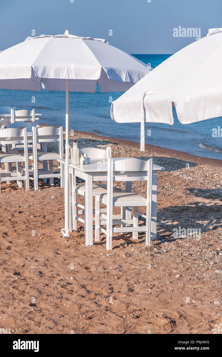 White wooden table on beach with blue sea with two chair and umbrella ...