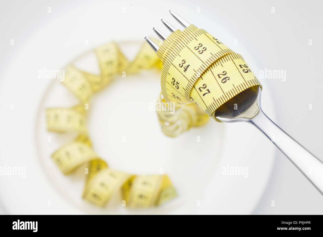 Diet concept, measuring tape looks like pasta put on fork, on white ...