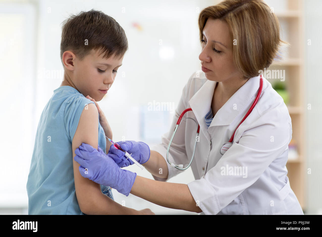 Doctor gives injection to boy's arm Stock Photo - Alamy