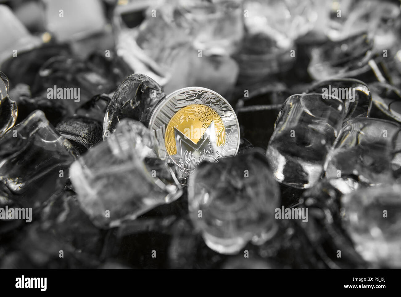 Digital currency physical metal gold monero coin on ice background. The ...