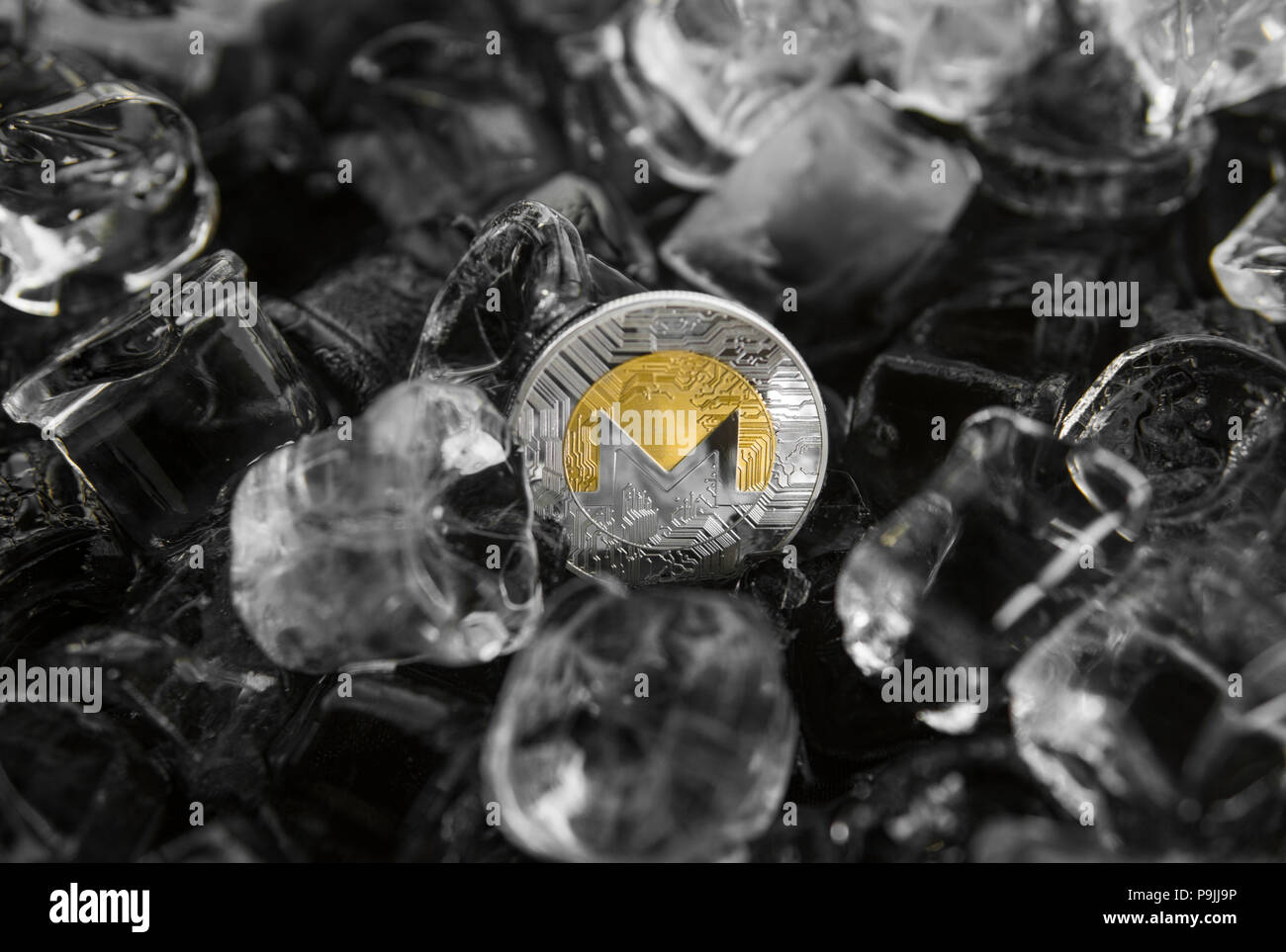 Digital currency physical metal gold monero coin on ice background. The ...