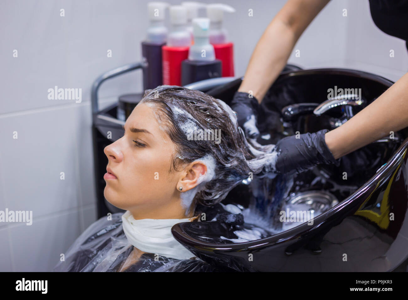 Professional hairdresser, stylist washing hair of woman client at salon ...