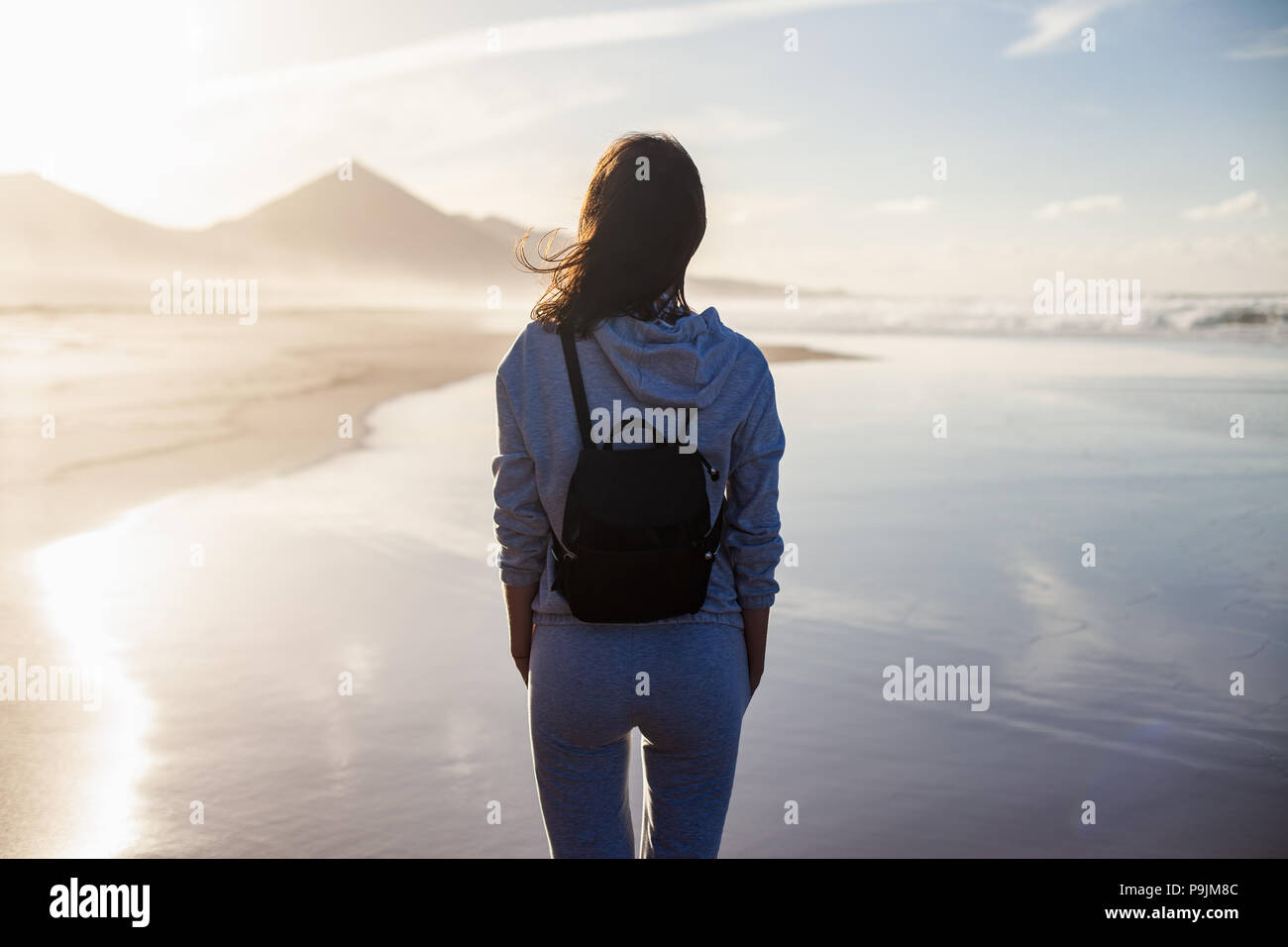 Back view of traveler woman enjoying ocean beach on sunset, Canary ...