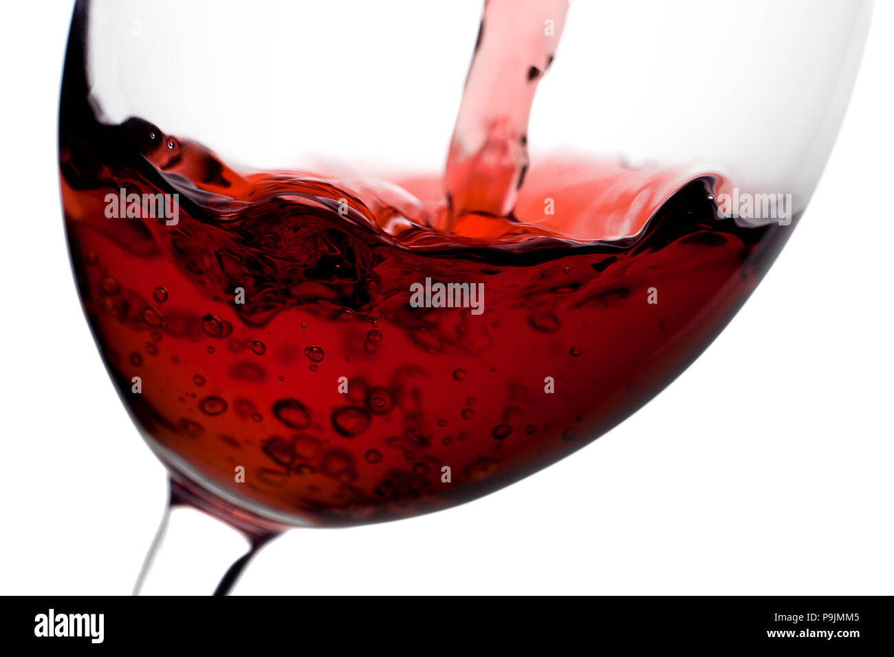 red wine poured from a bottle into wineglass on white background Stock ...