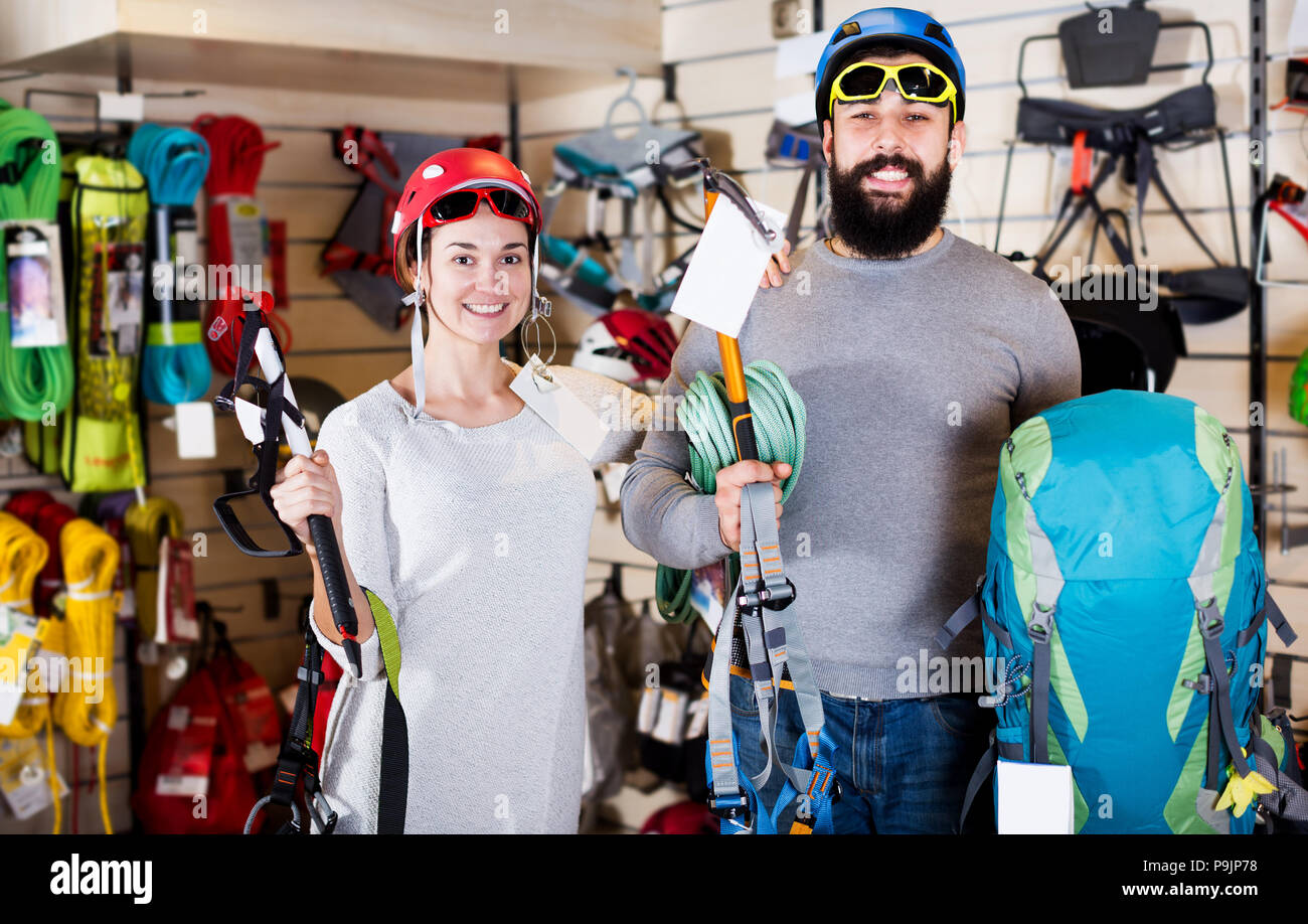 Young happy couple deciding on climbing equipment in sports equipment ...