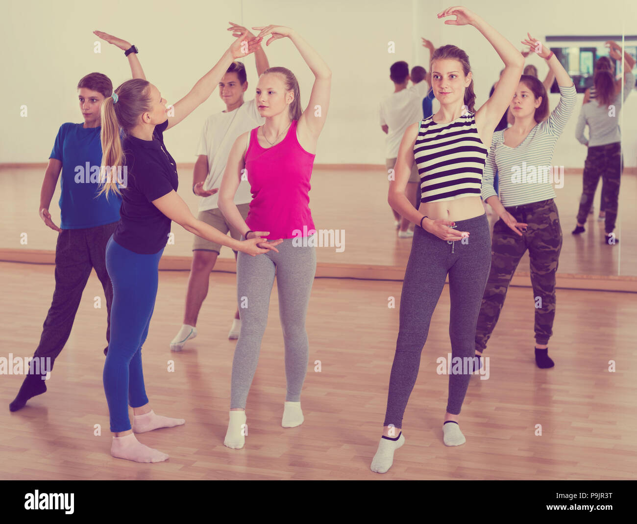 Group of teenage boys and girls studying ballet dance in dance hall ...
