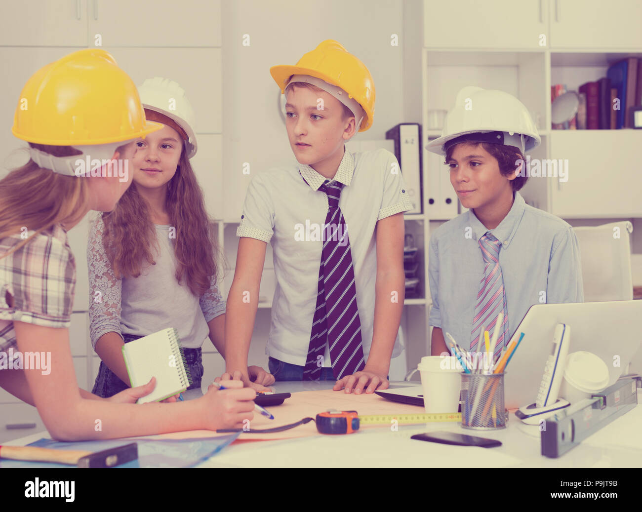 Group of children in helmet talking about building near laptop Stock ...