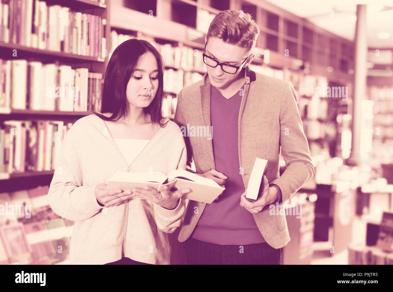 handsome young students studying in library, reading and discussing ...
