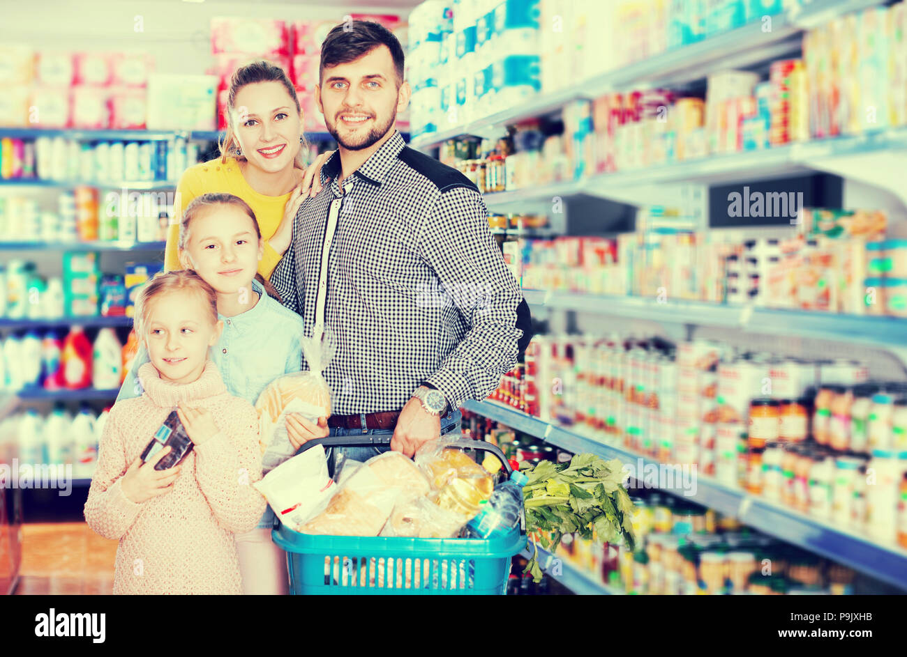 portrait of parents with two little girls with purchases during family ...