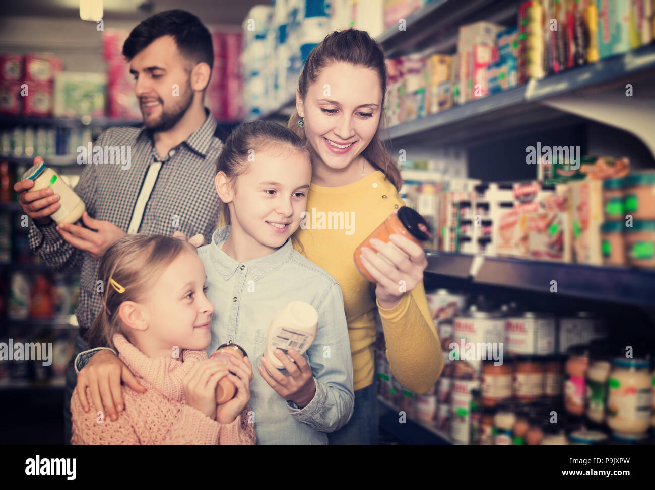 positive family of four shopping together in grocery store Stock Photo ...