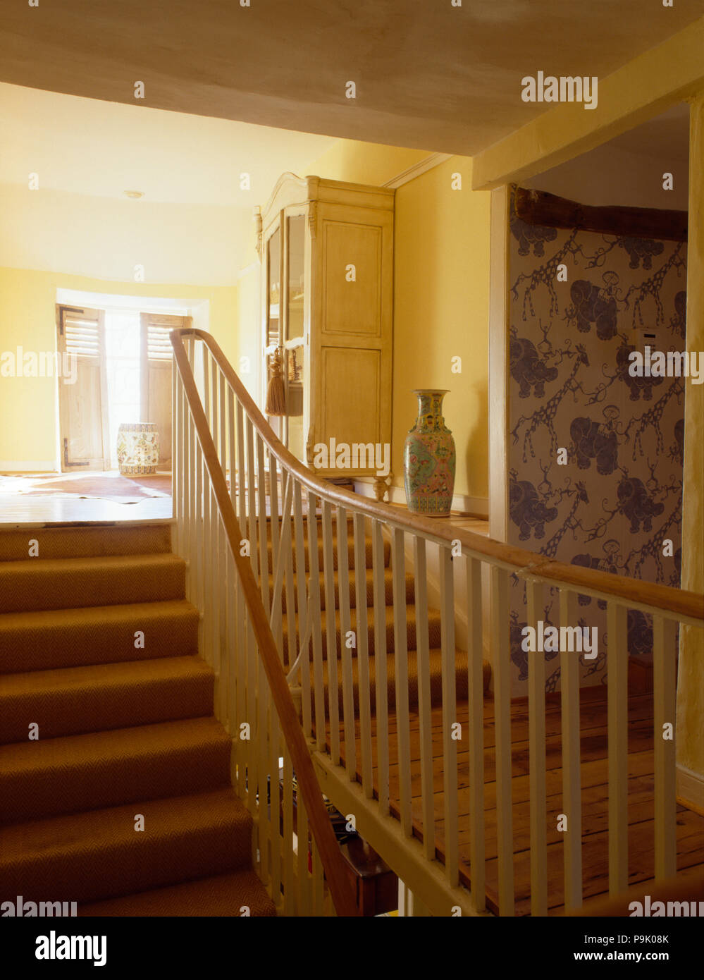 Neutral carpet and painted bannisters on stairs to a yellow country ...