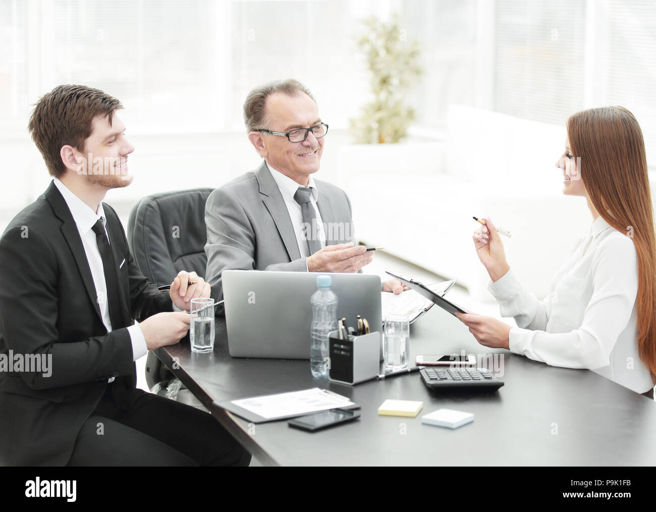 Manager discussing work issues with his assistants behind a Desk Stock ...
