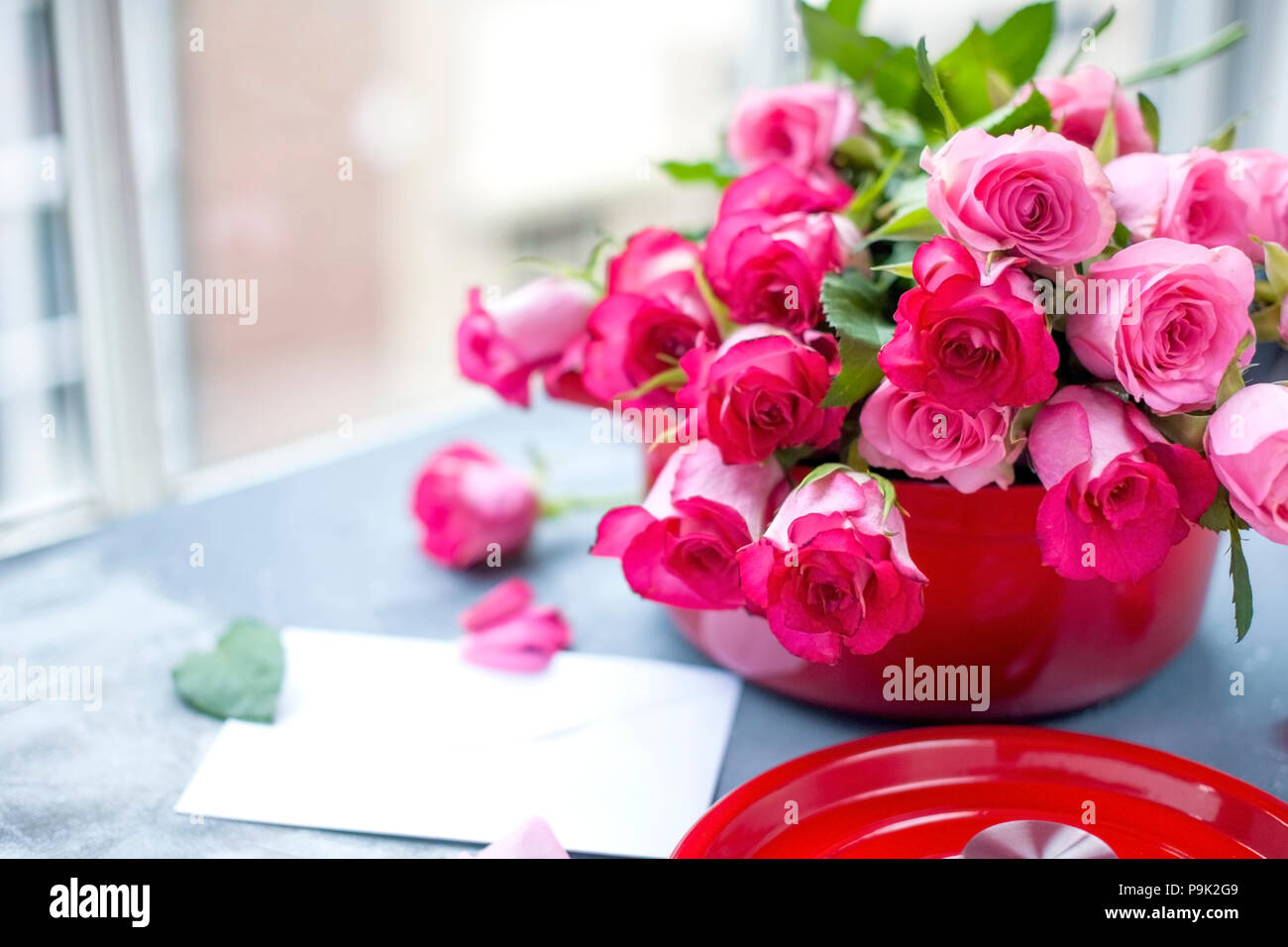 A bouquet of fresh pink roses, in a pan of red cast iron, on a gray ...