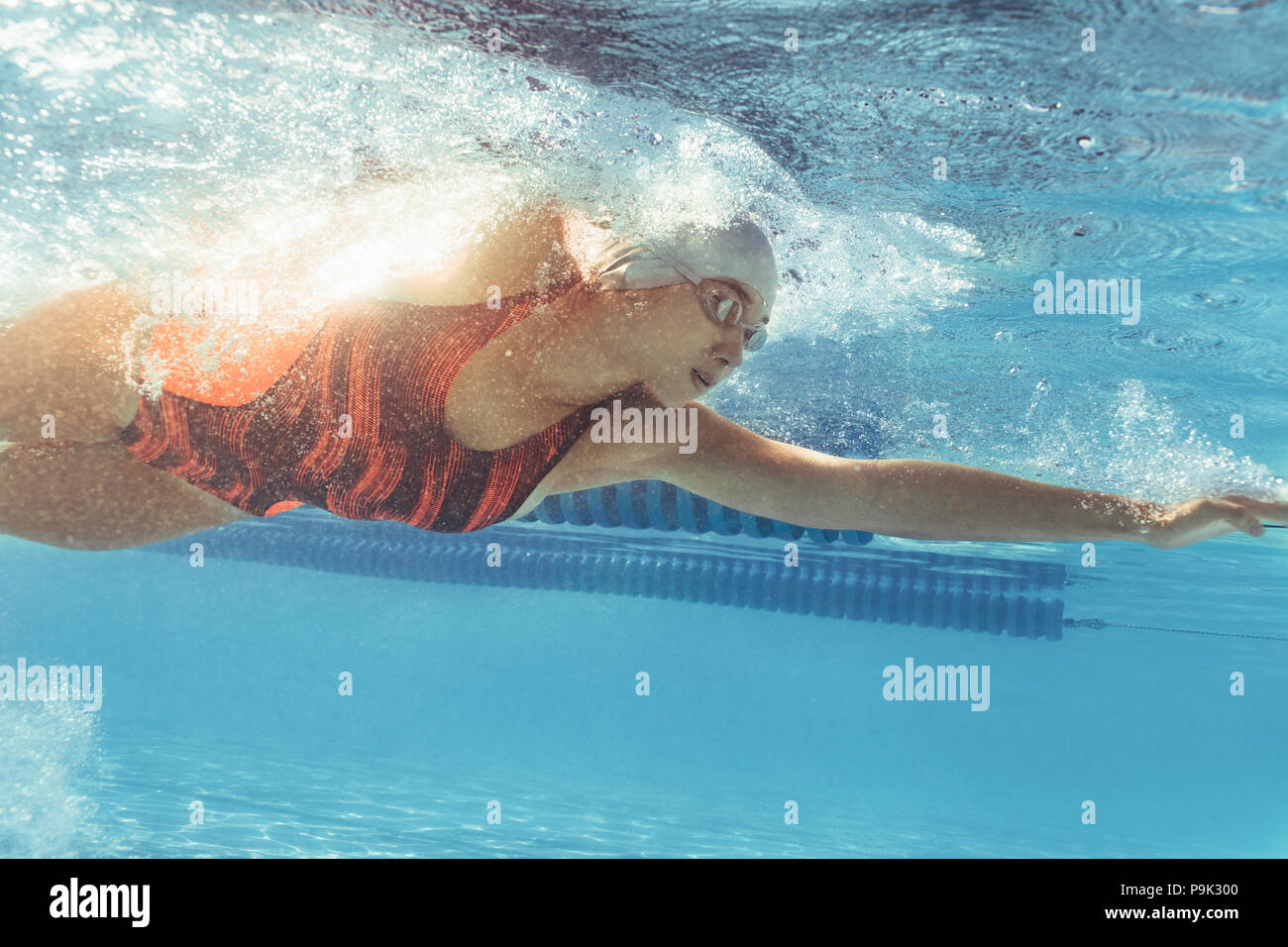 Underwater shot of young woman swimming in pool. Female swimmer inside ...