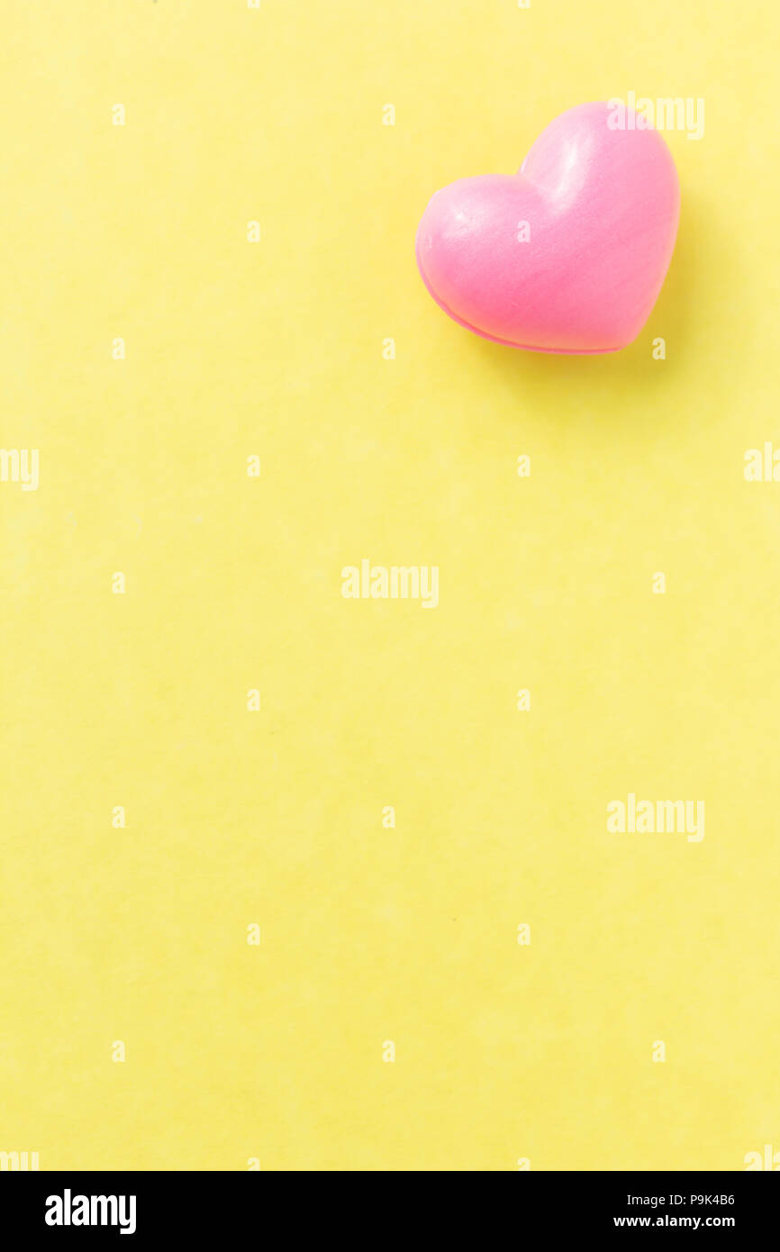 Red heart shape over yellow table. Top view of romantic symbol of ...