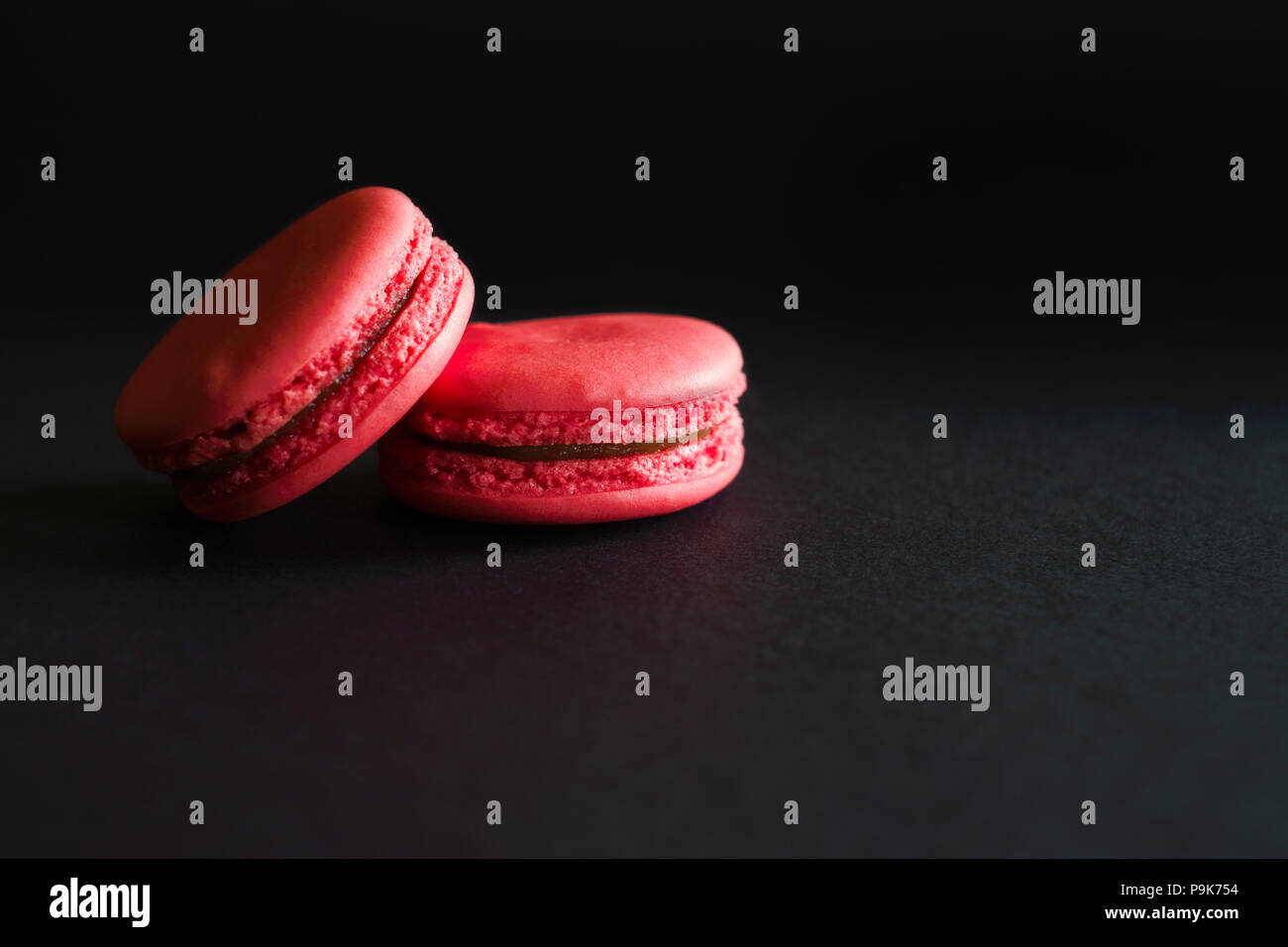 Sweet red french macaron on dark background Stock Photo - Alamy