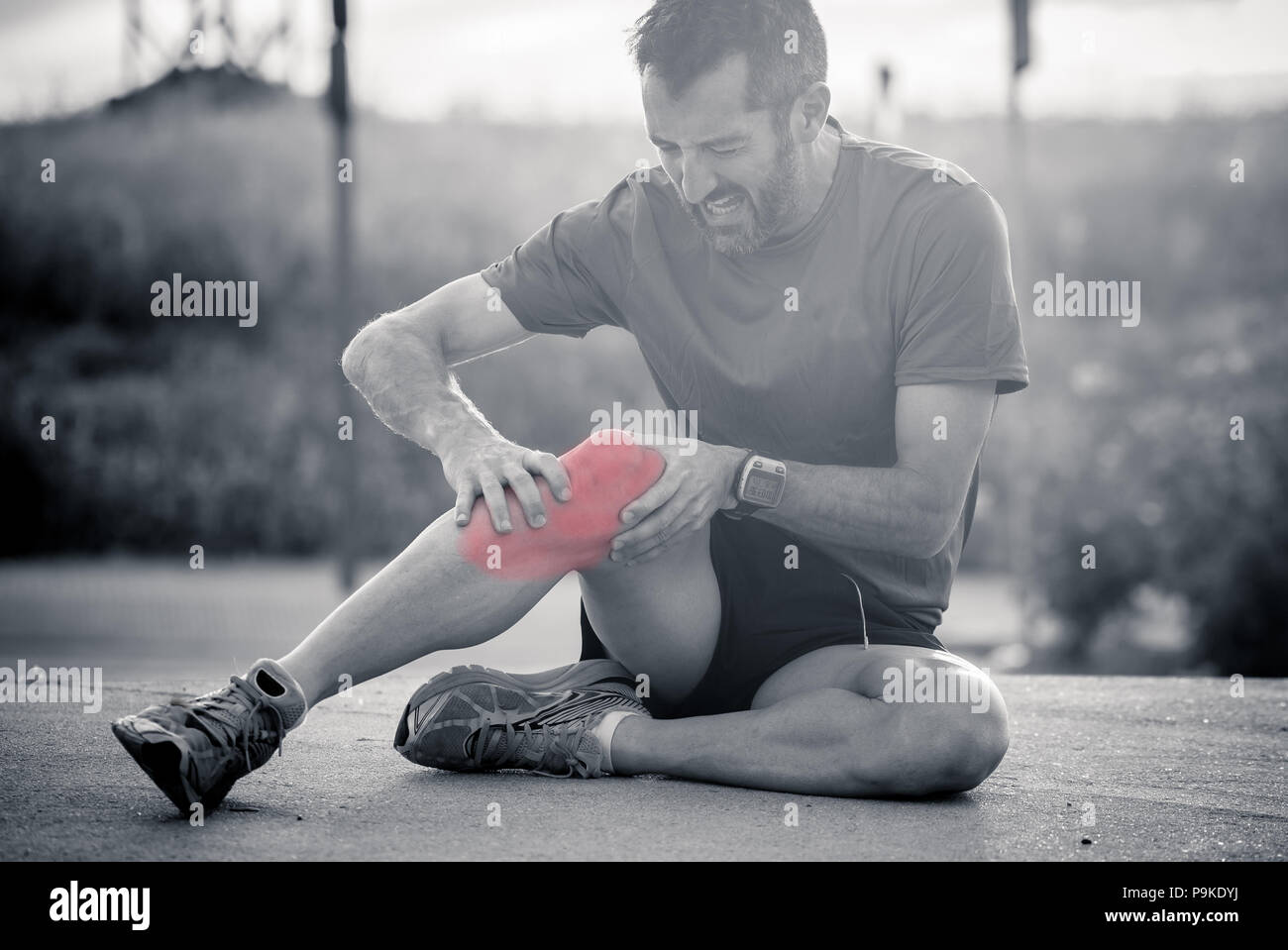 Closeup black and white of sport guy runner injuring his knee after a ...