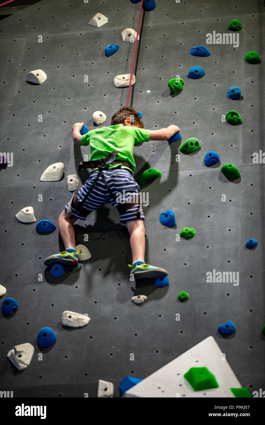 Young boy climbing up on practice wall in indoor rock gym Stock Photo ...