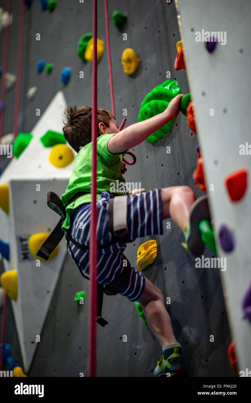 Young boy climbing up on practice wall in indoor rock gym Stock Photo ...