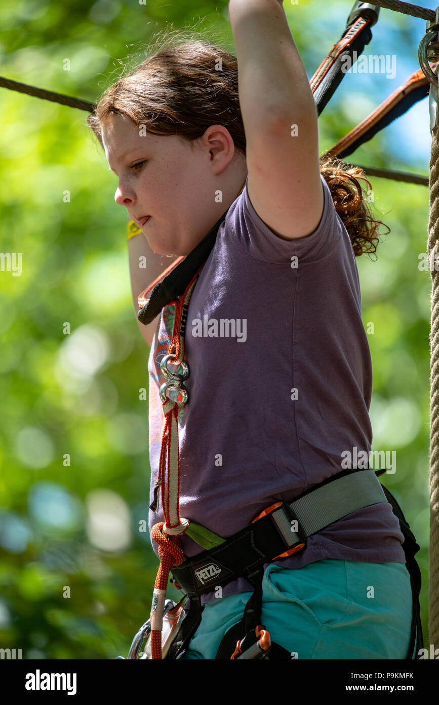 Portrait of a beautiful girl on a rope park among trees. Children ...