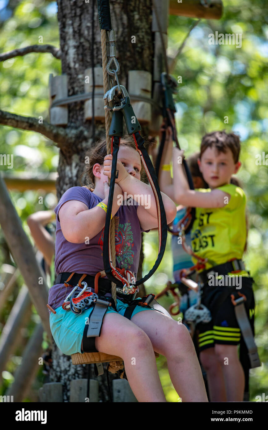 Portrait of a beautiful girl on a rope park among trees. Children ...