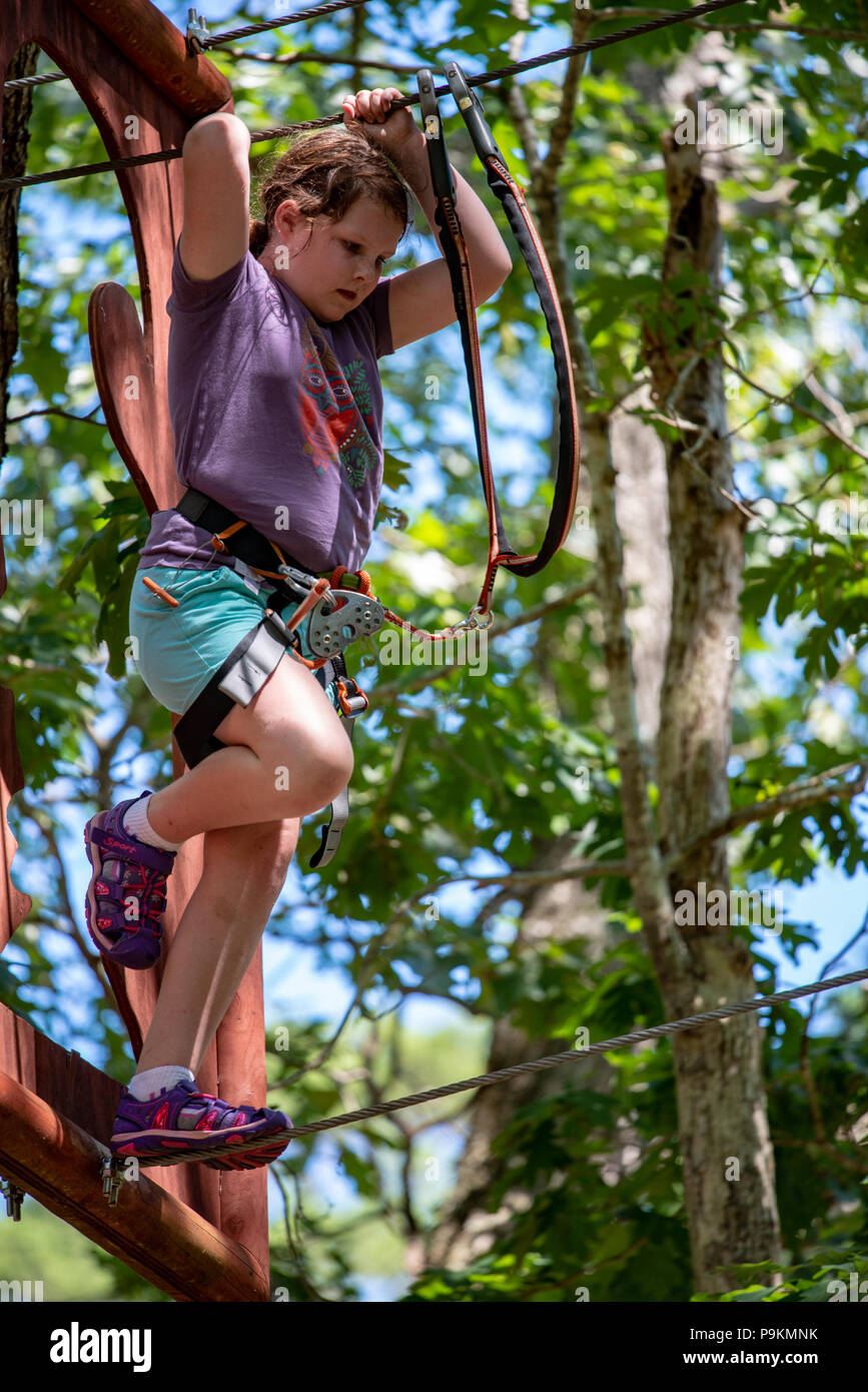 Portrait of a beautiful girl on a rope park among trees. Children ...