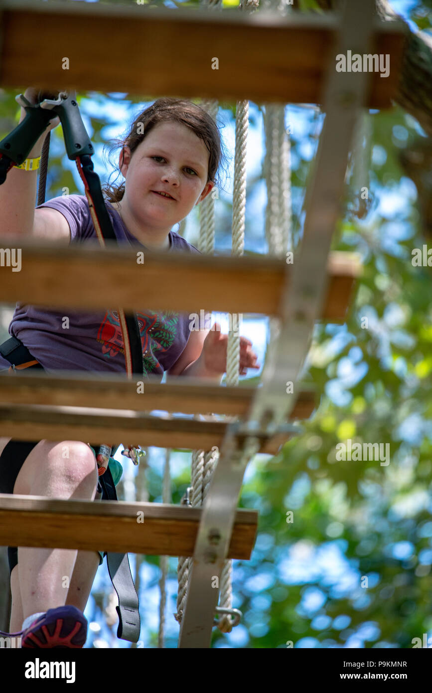 Portrait of a beautiful girl on a rope park among trees. Children ...