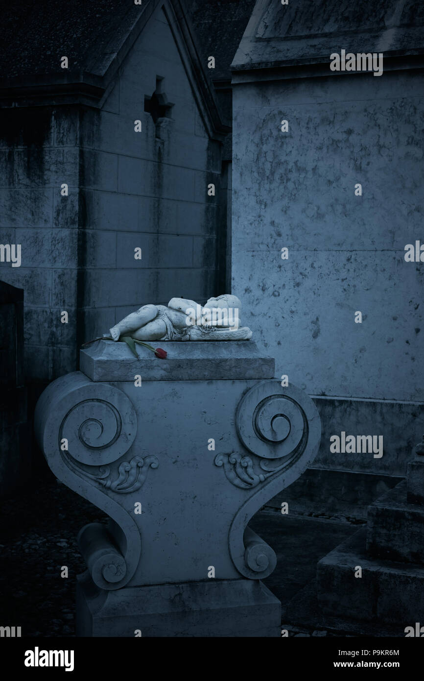 Old and sad white marble statue of a child sleeping in the middle of a ...