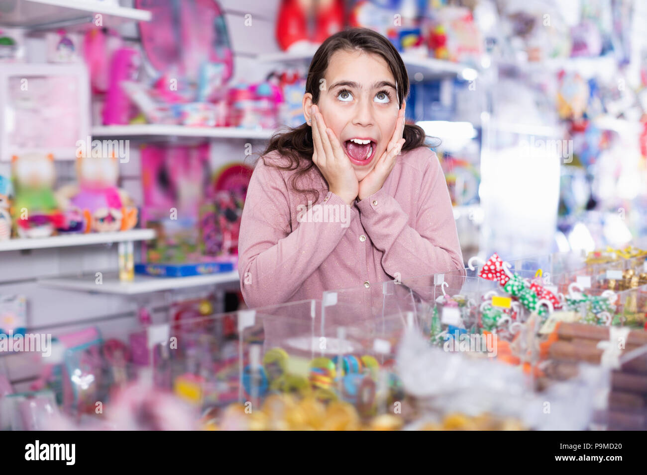 Emotional happy small girl choosing sweet candies in the candy shop ...