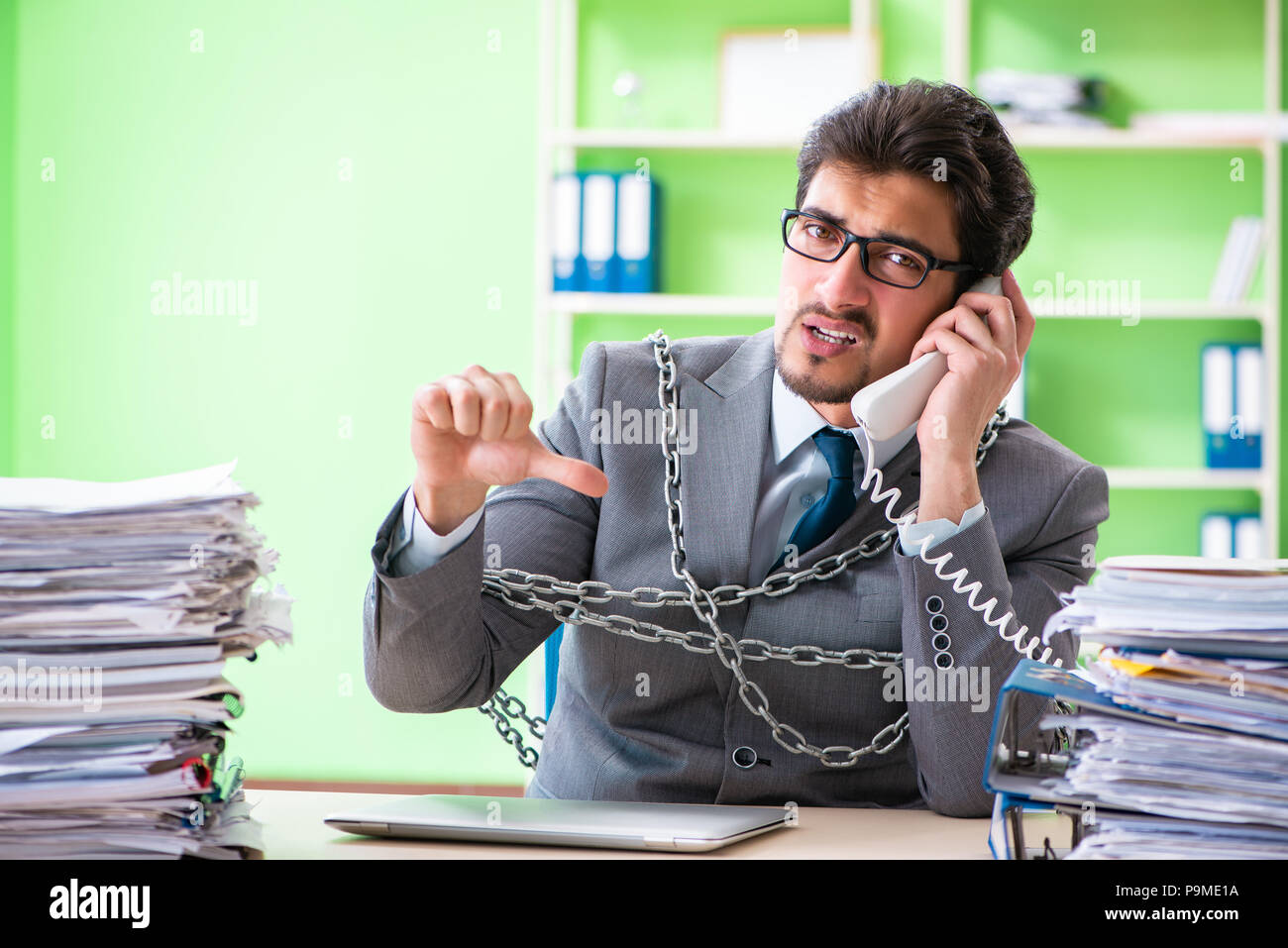 Employee chained to his desk due to workload Stock Photo - Alamy