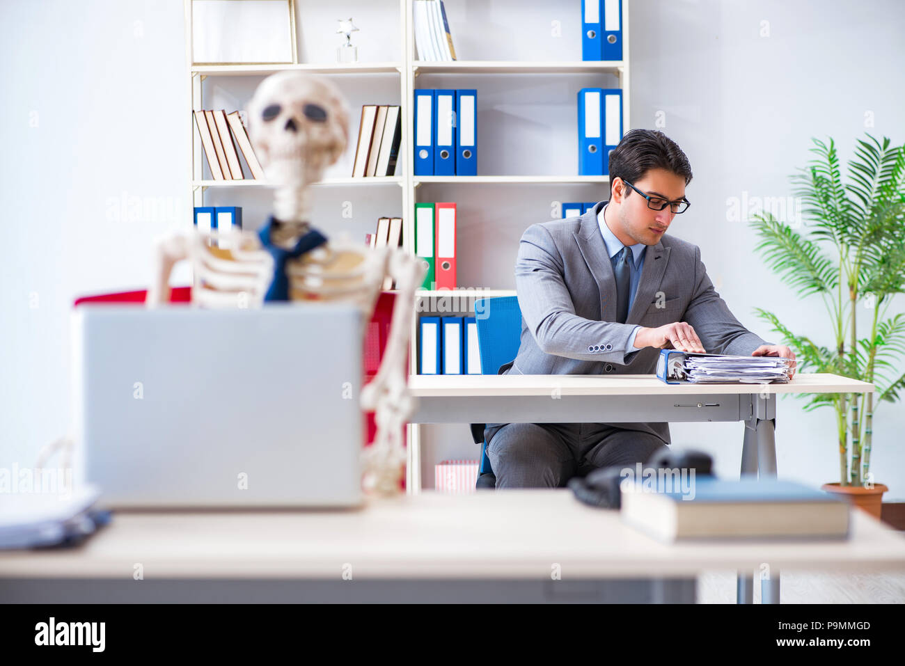 Businessman working with skeleton in office Stock Photo - Alamy