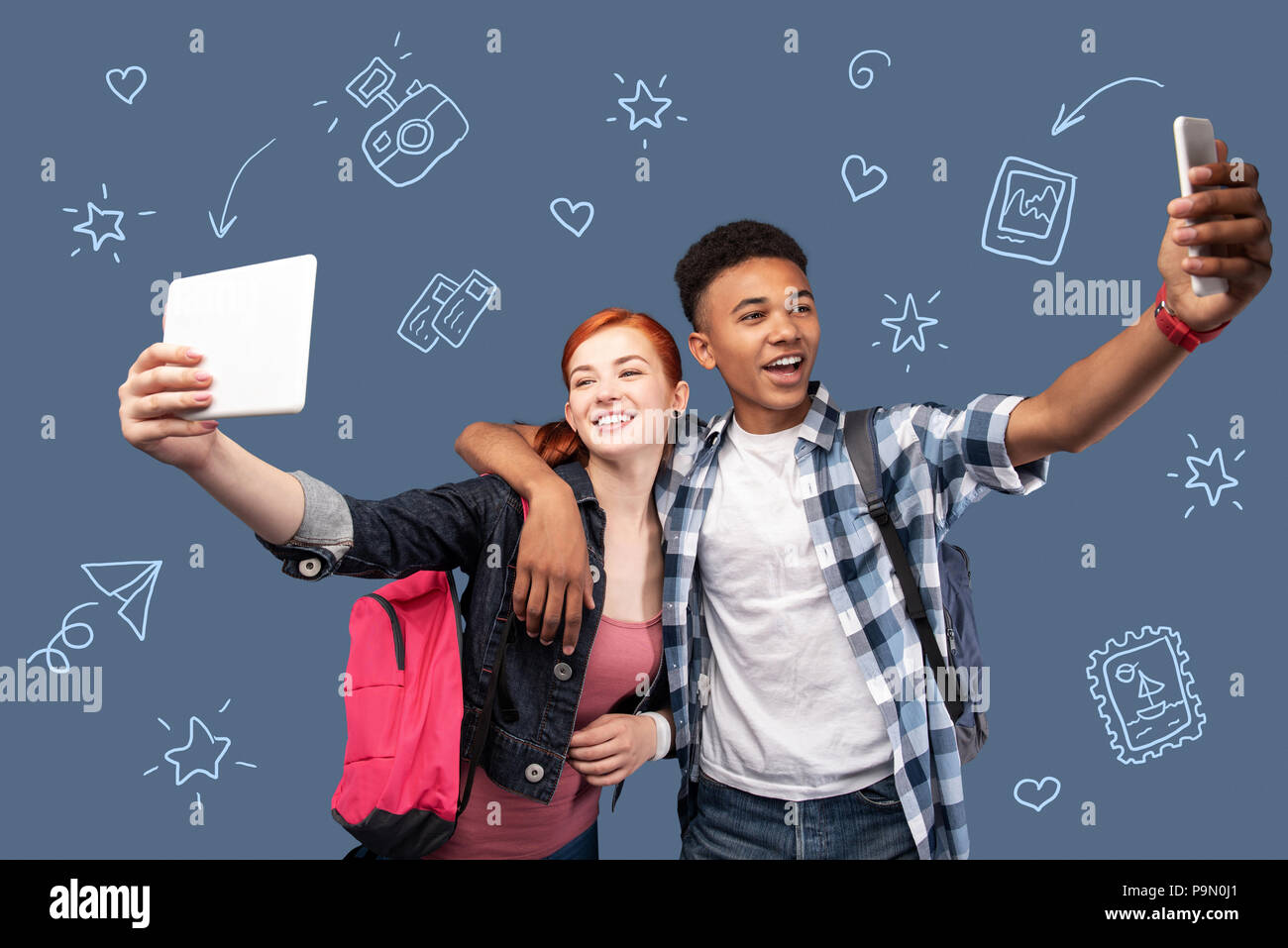 Friendly teenagers holding modern gadgets and taking selfies Stock ...