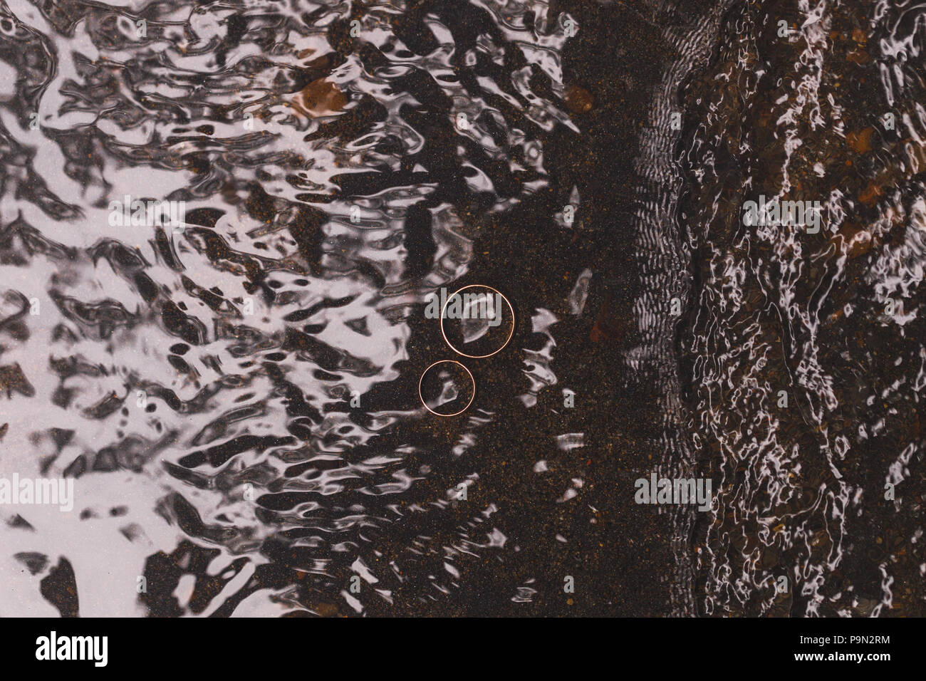 Wedding rings on water surface texture Stock Photo - Alamy