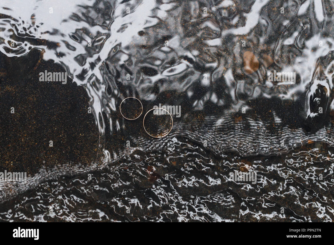 Wedding rings on water surface texture Stock Photo - Alamy