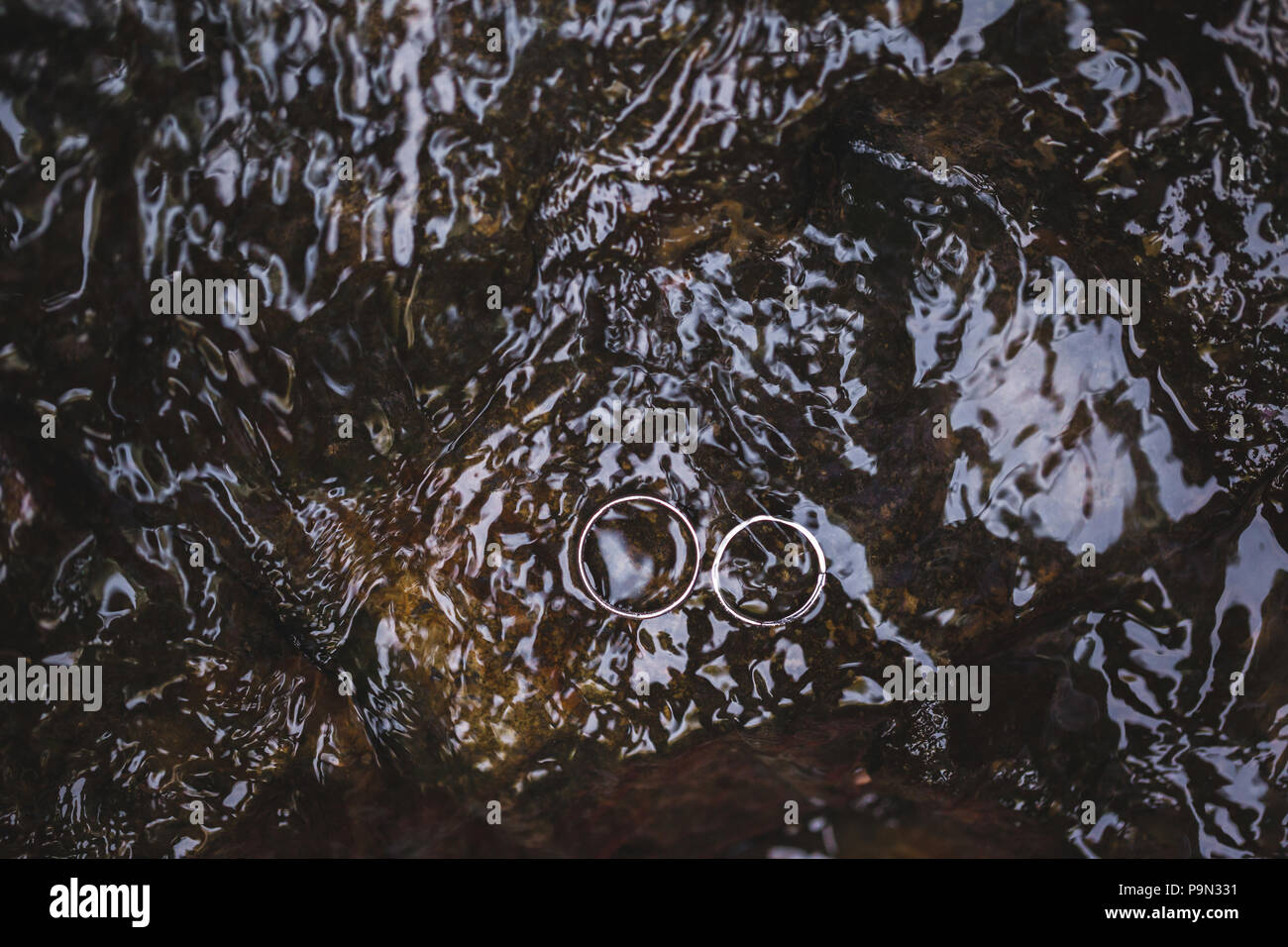 Wedding rings on water surface texture Stock Photo - Alamy