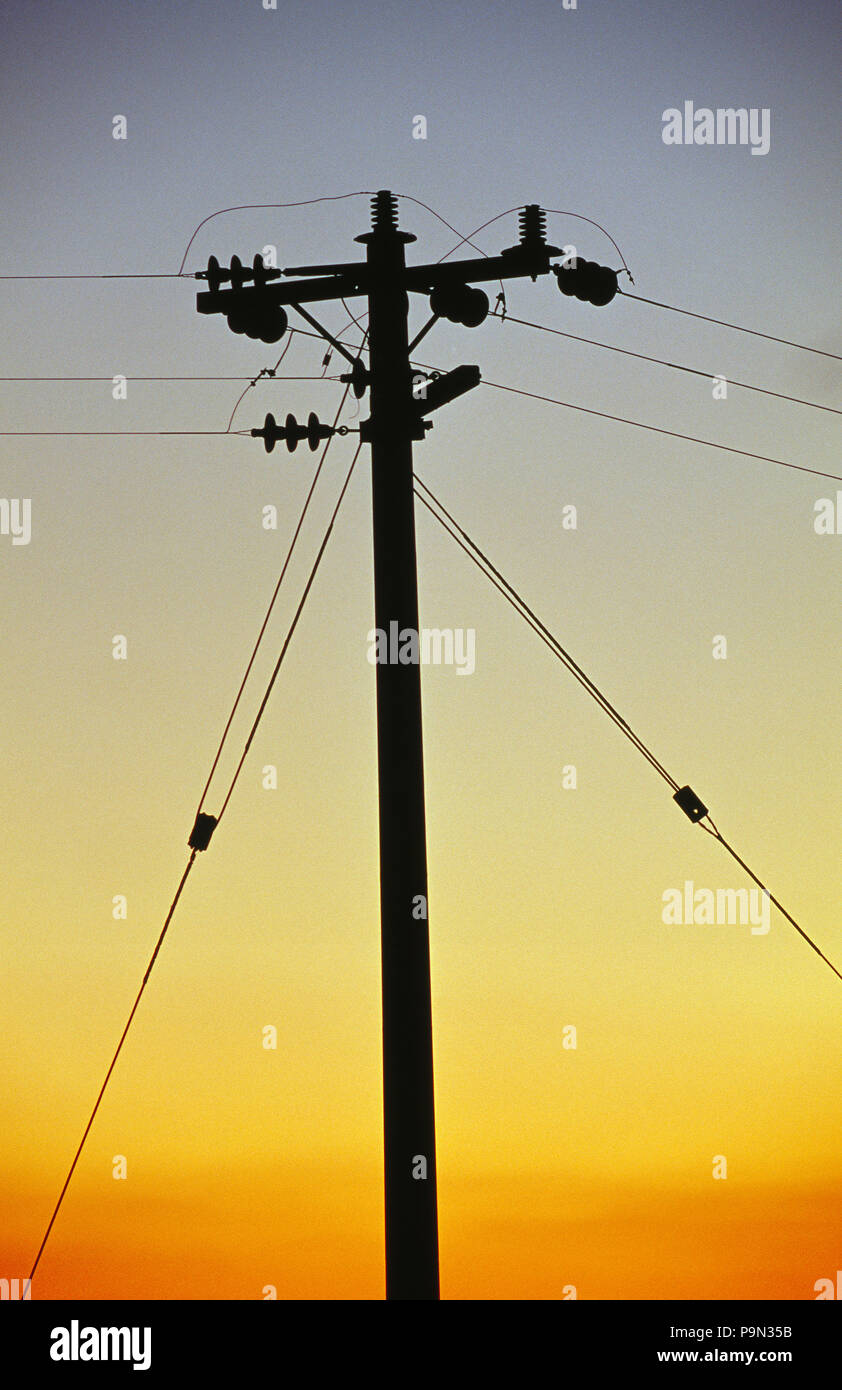 Sunset silhouettes an electricity pole and wires in rural Australia ...