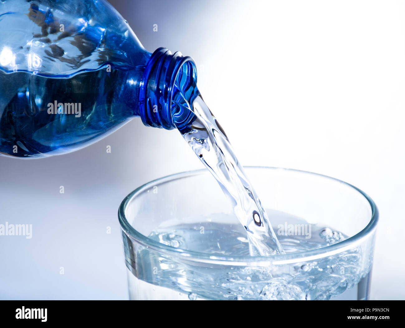 Pouring of cold clear drink water from bottle into glass, close up ...