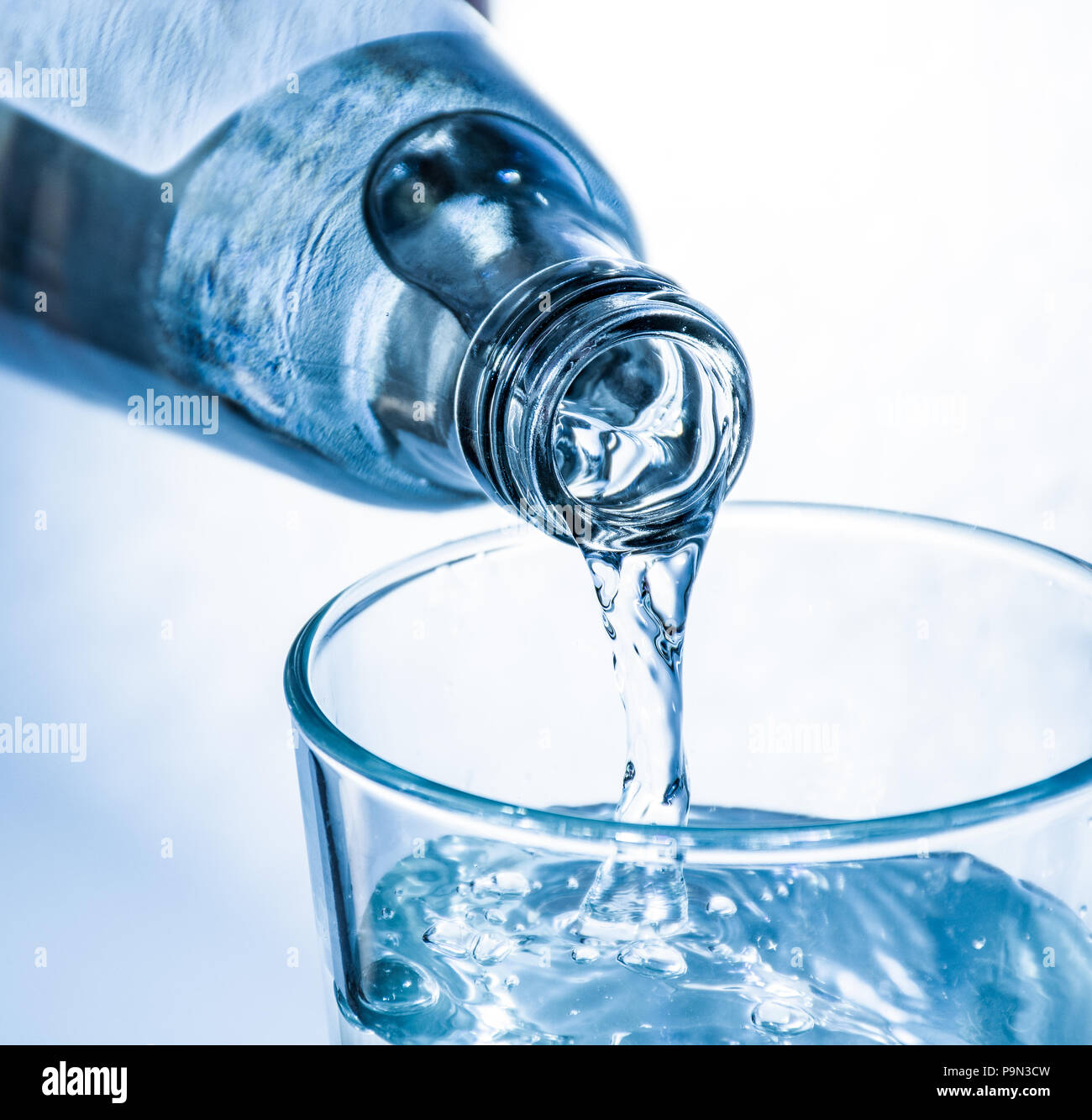 Pouring of cold clear drink water from bottle into glass, close up ...