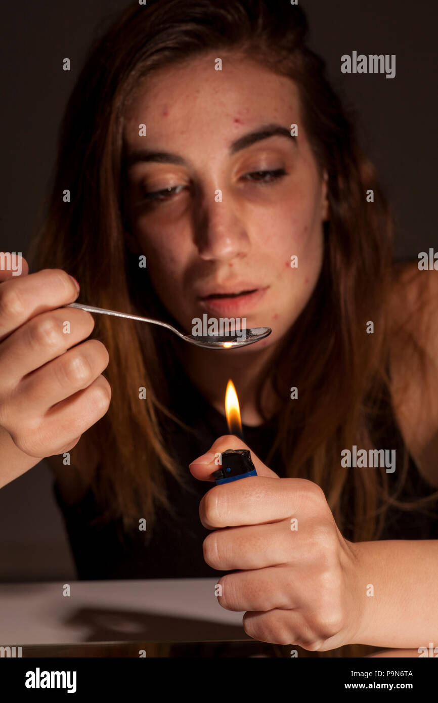 a young drug-addict woman lheated spoon with lighter Stock Photo - Alamy