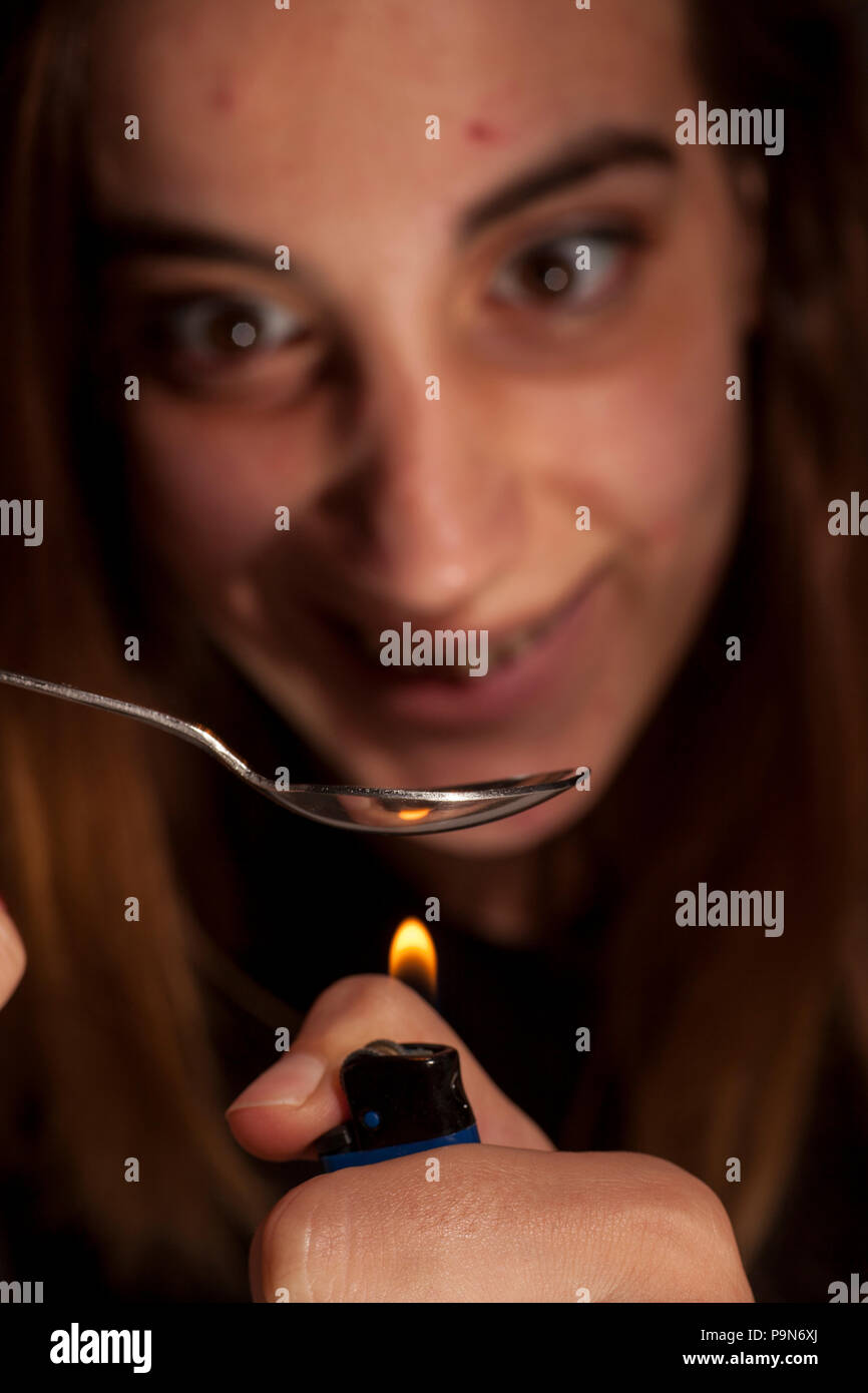 a young drug-addict woman lheated spoon with lighter Stock Photo - Alamy