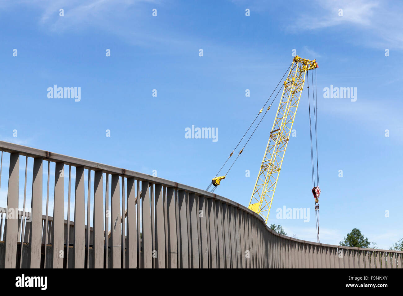 metal fences and a yellow construction crane against the blue sky, a ...