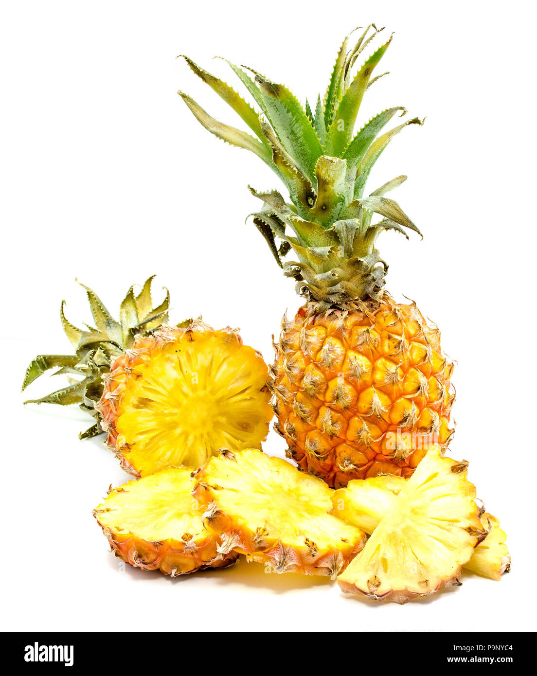 Fresh round pineapple slices and one whole pineapple with green leaves ...