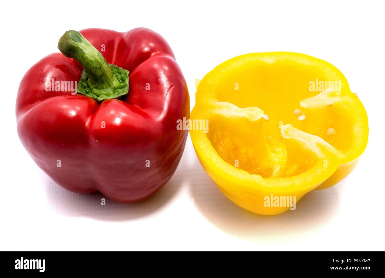 One whole red pepper and cut yellow pepper isolated on white background ...