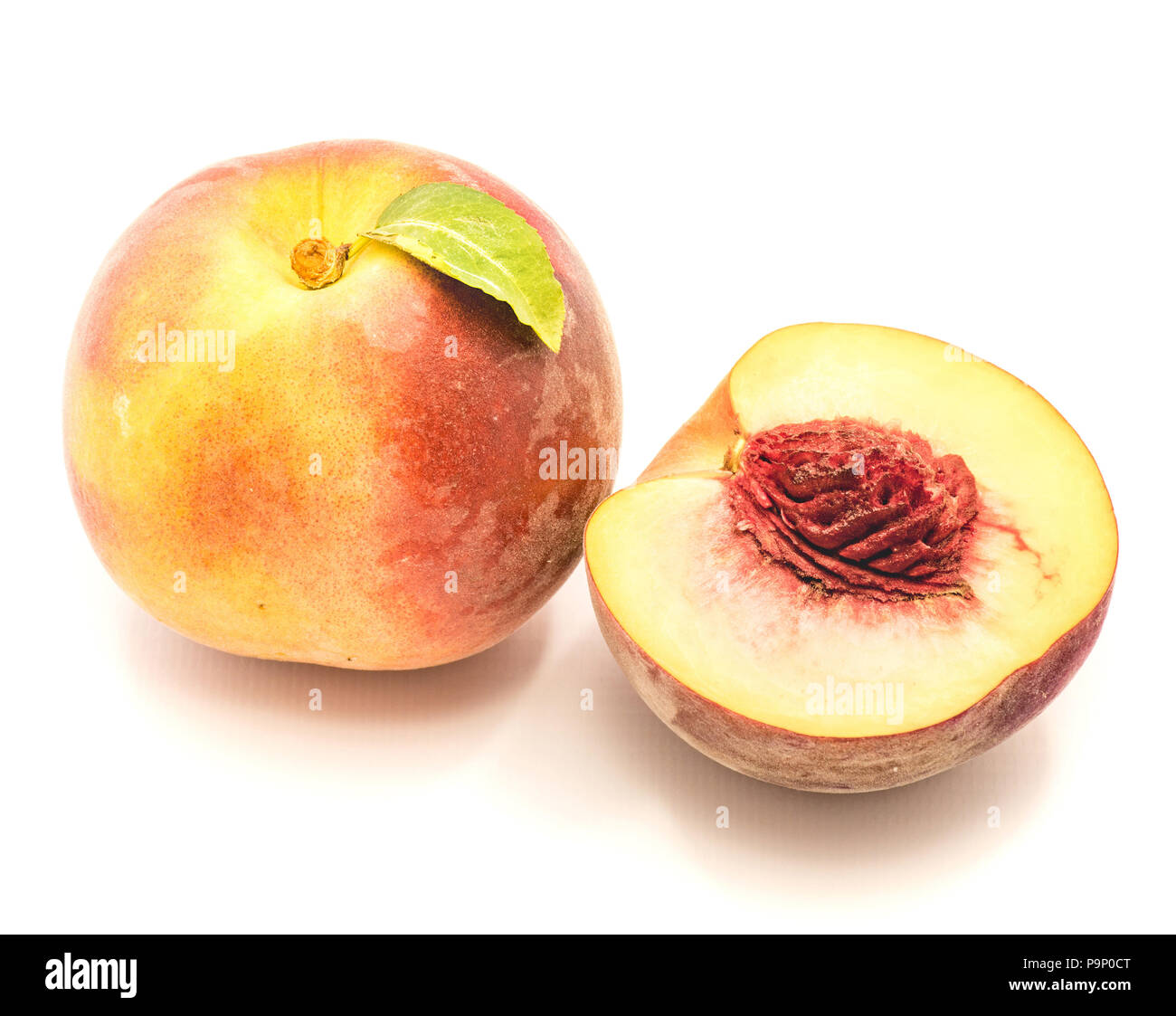 One whole peach and cut half with a corrugated stone isolated on white ...