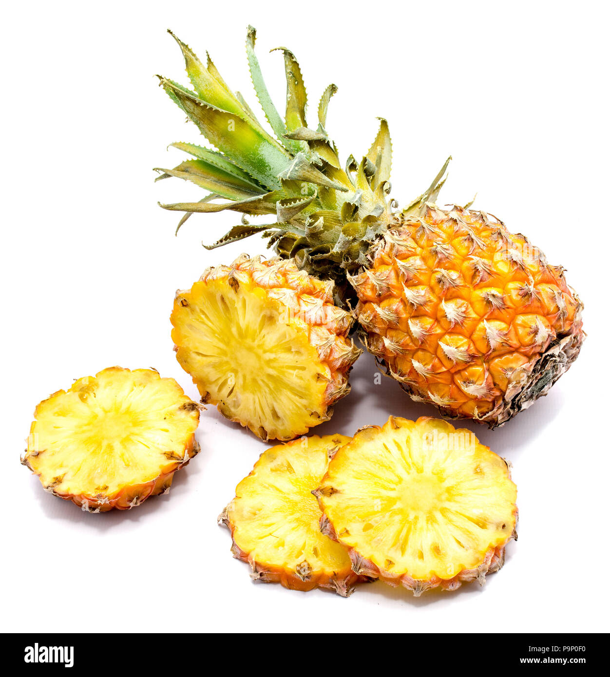 Fresh round pineapple slices and one whole pineapple with green leaves ...
